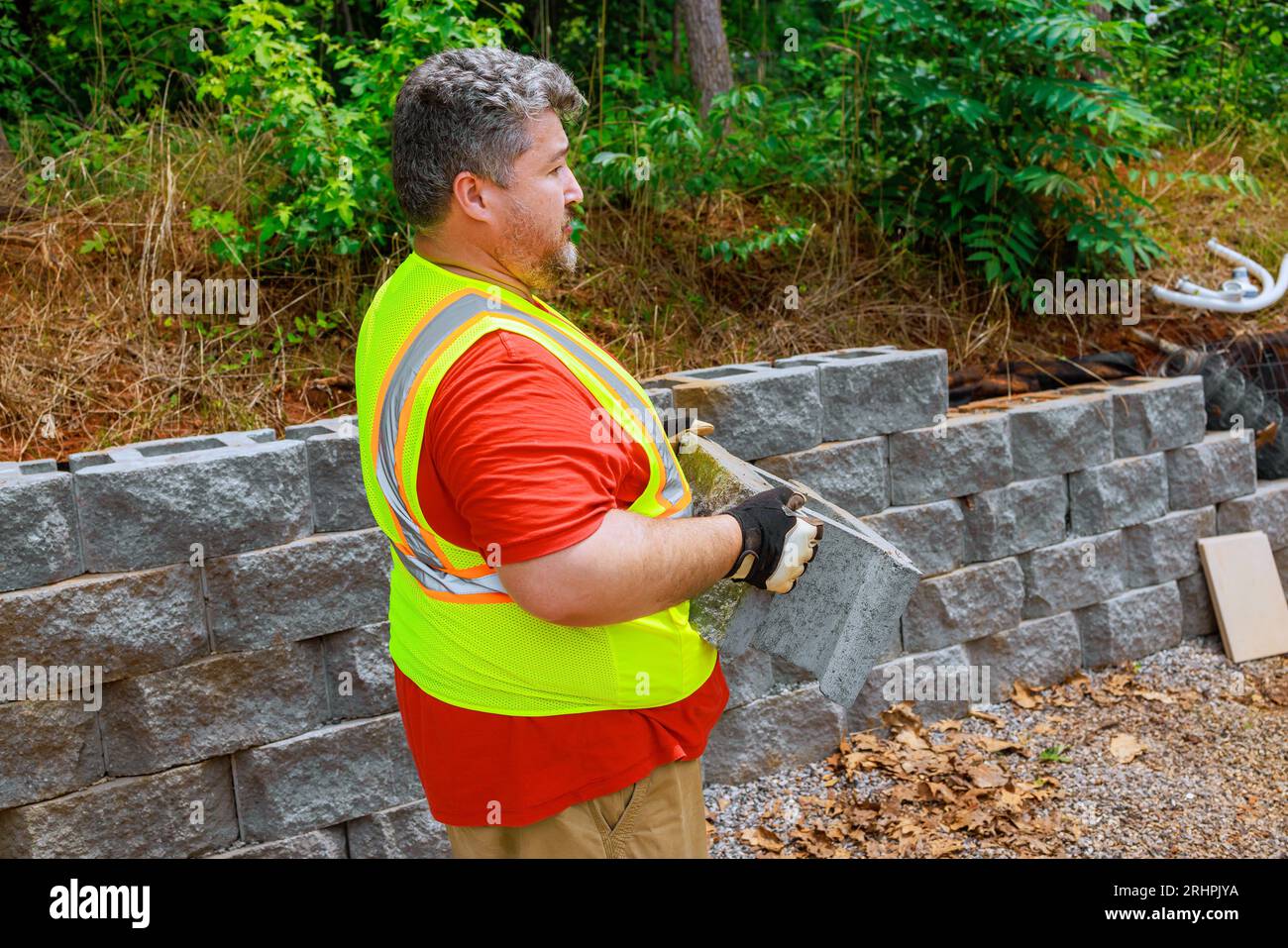 Construction worker lifted concrete block positioned it on retaining ...