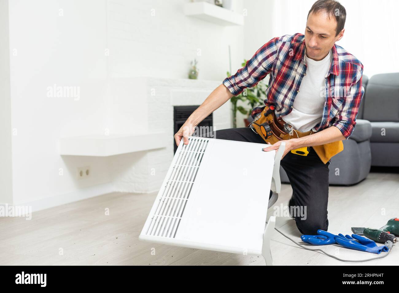 Workman mounting water heating radiator near the window in the white ...