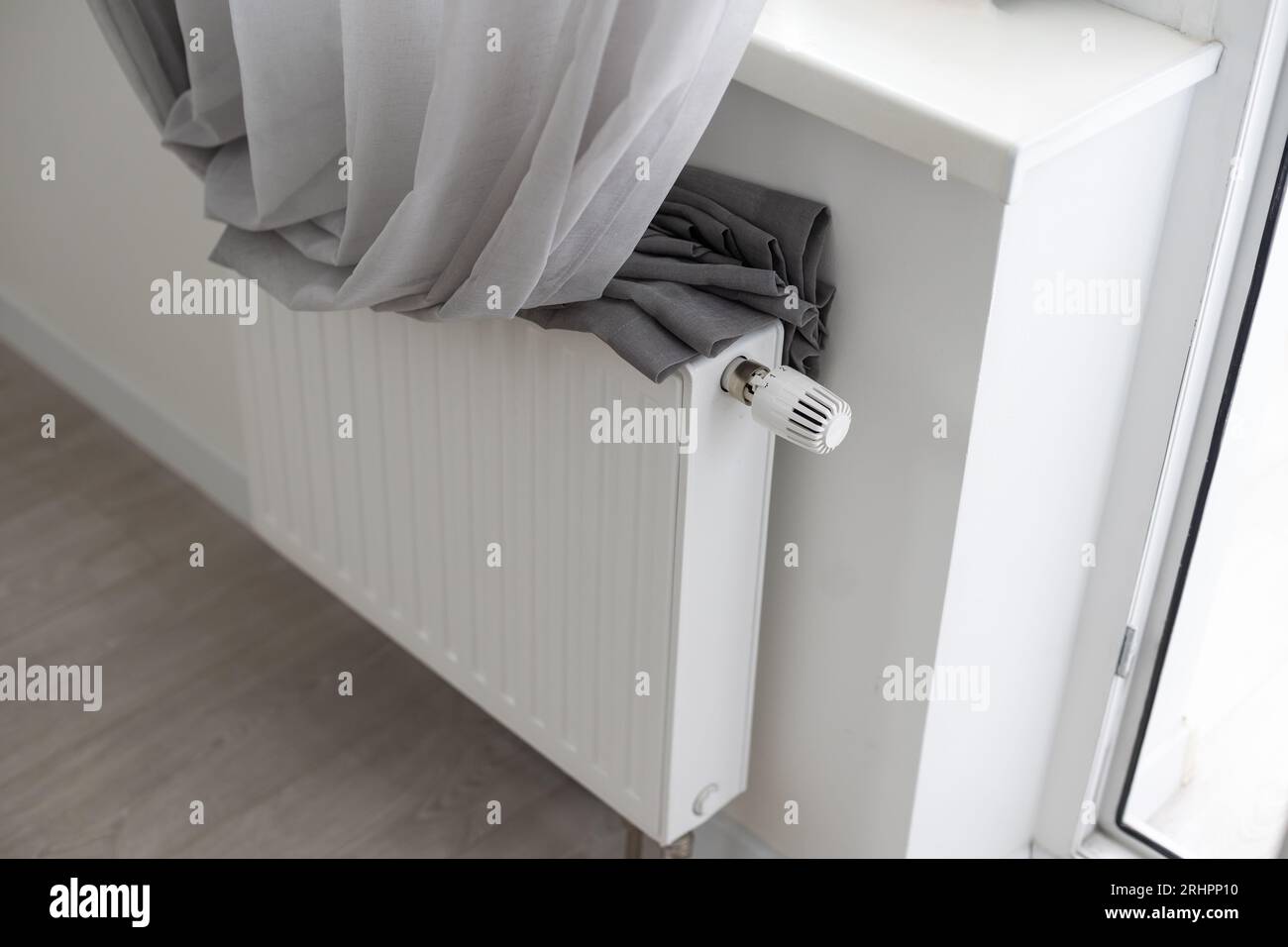 A steel panel heating radiator is placed under the windowsill on a ...