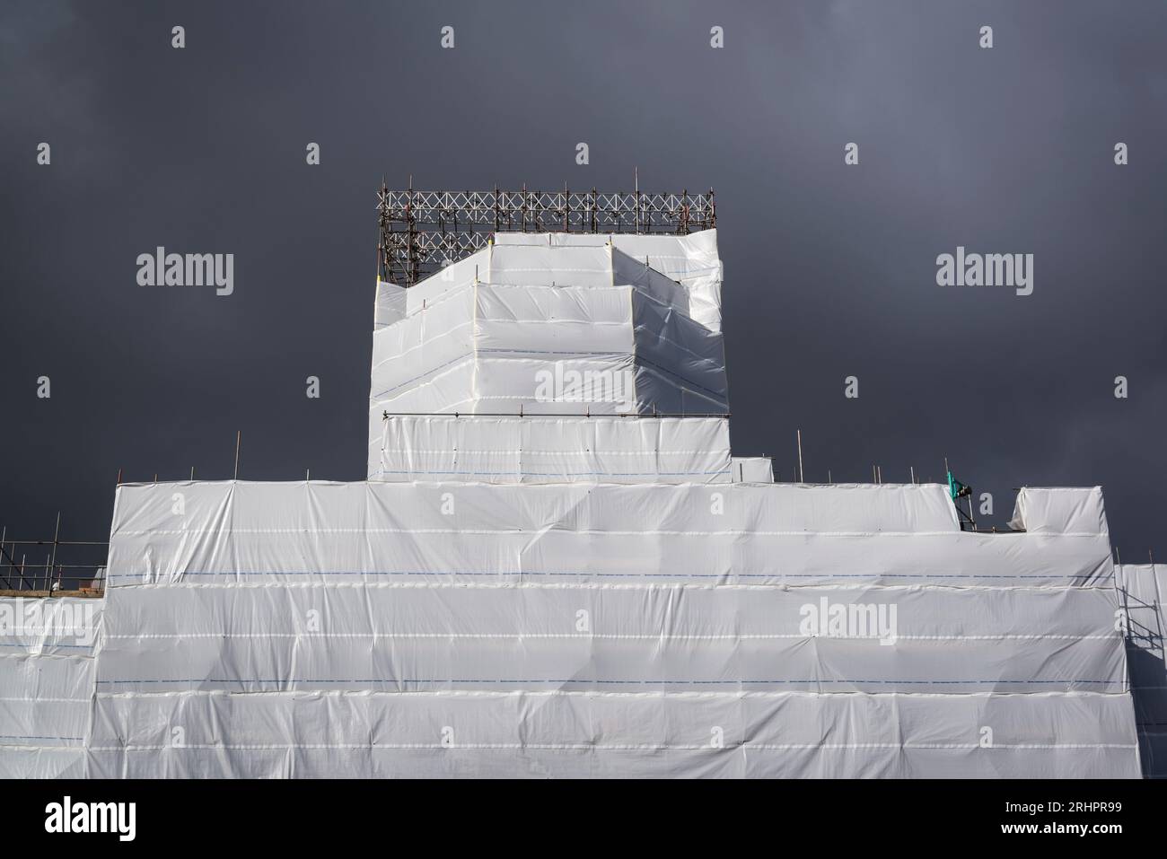 Building covered in scaffolding sheets against moody sky, London ...