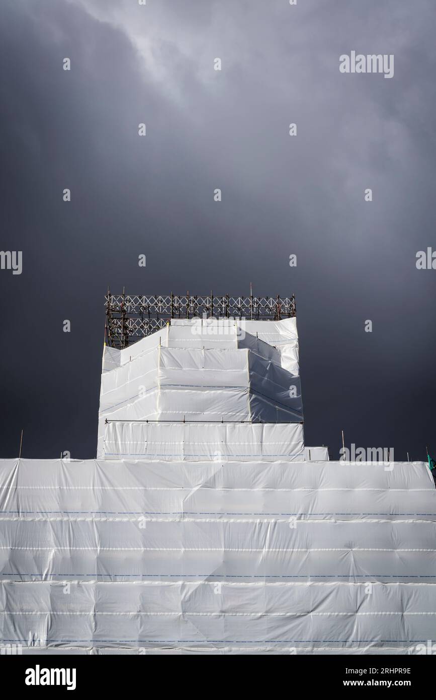 Building covered in scaffolding sheets against moody sky, London ...