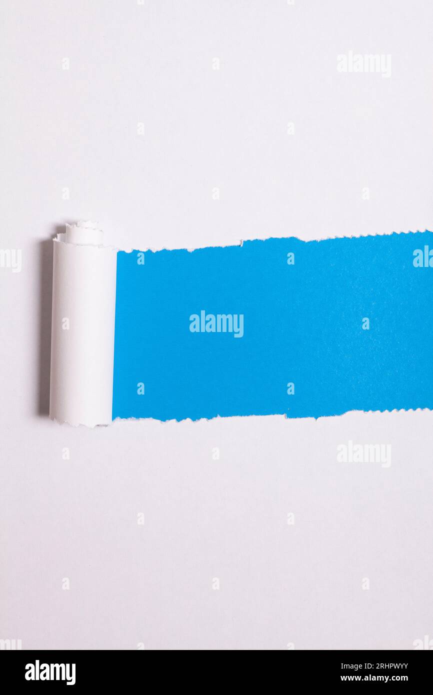 Torn paper with opening showing blue background Stock Photo - Alamy