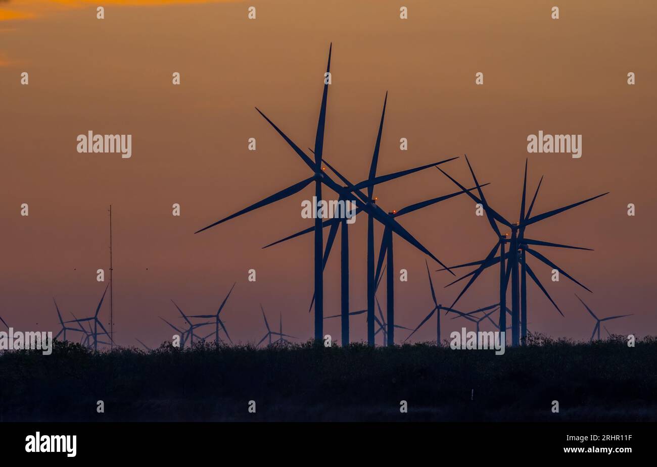 A collection of wind powered generators standing tall against a Texas ...