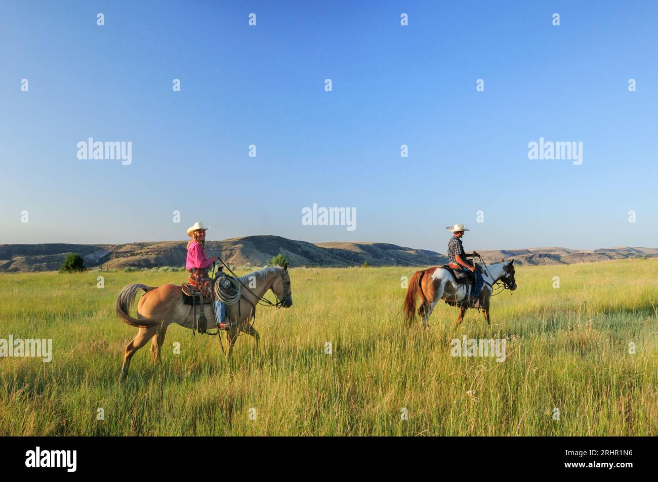 Cowboy and Cowgirl riding through grassland, Wilson ranch, near the ...