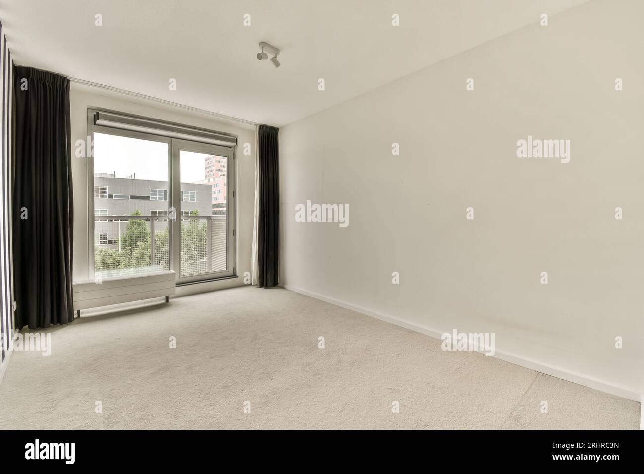 an empty room with white walls and black drapes on the window is ...