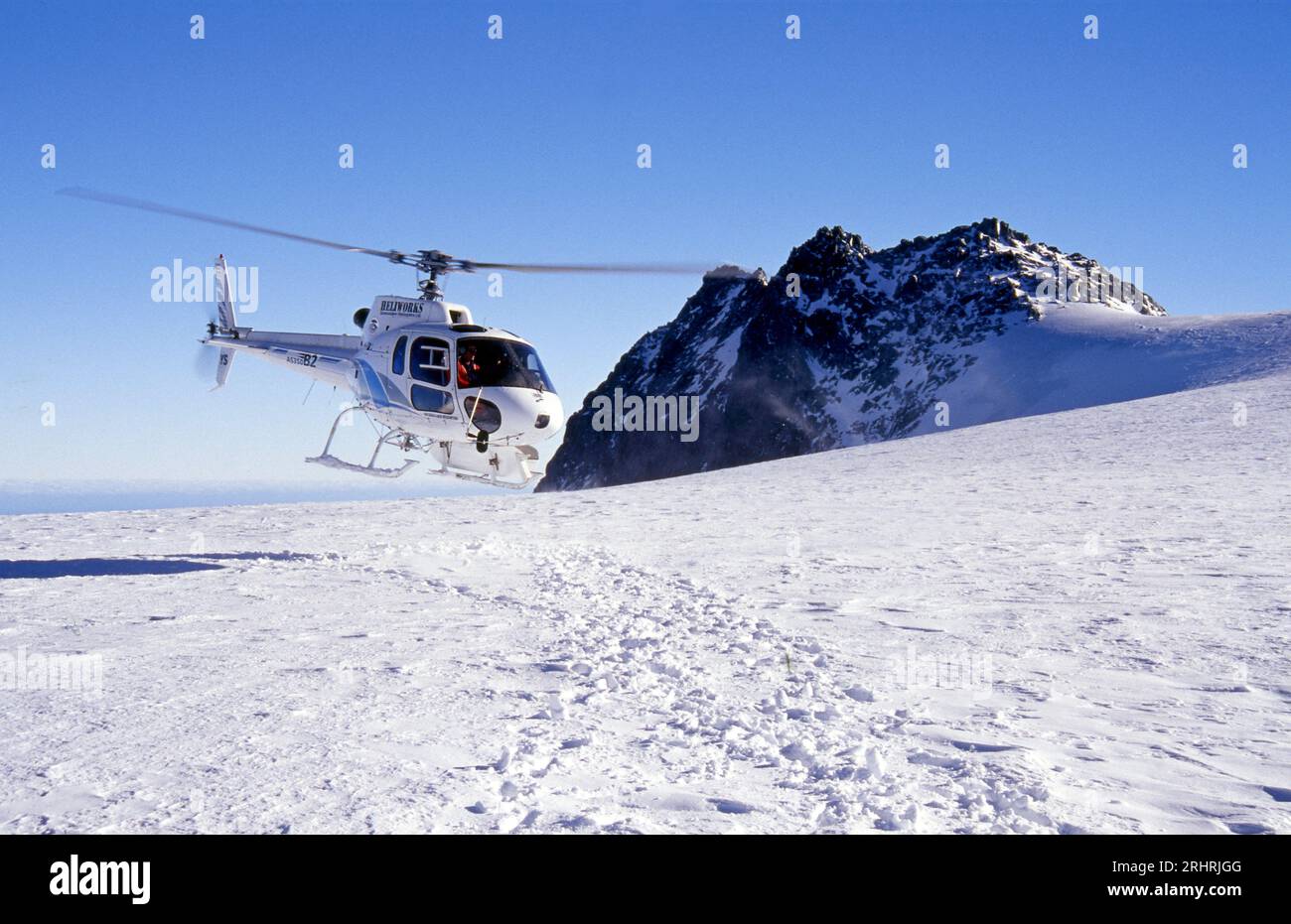A helicopter for adventure tourism takes off from a remote snow-capped ...