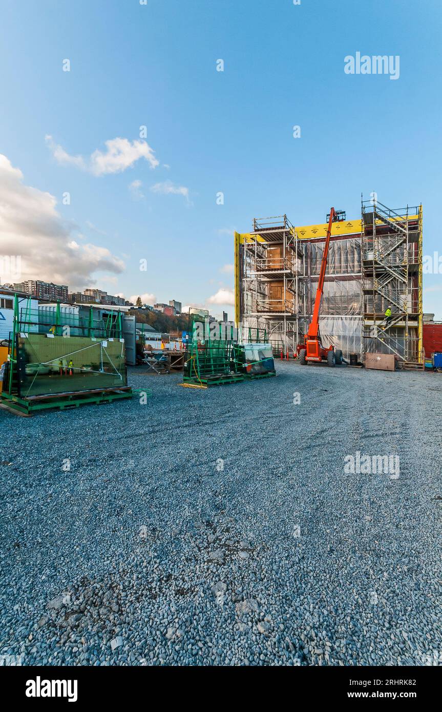 An orange rental high-lift with its arm extended to roof of building at ...