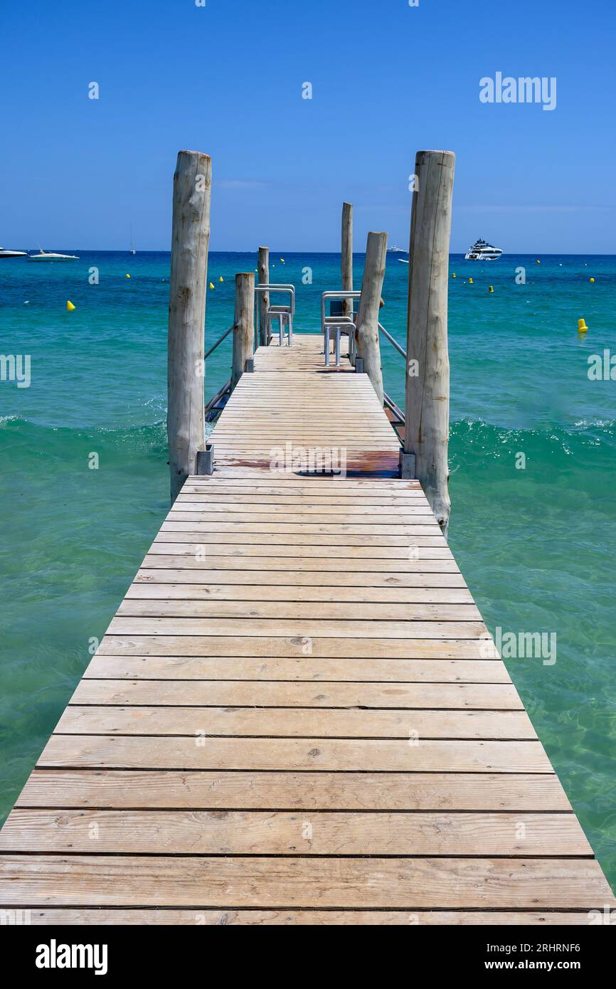 Wooden pier and crystal clear blue water of legendary Pampelonne beach ...