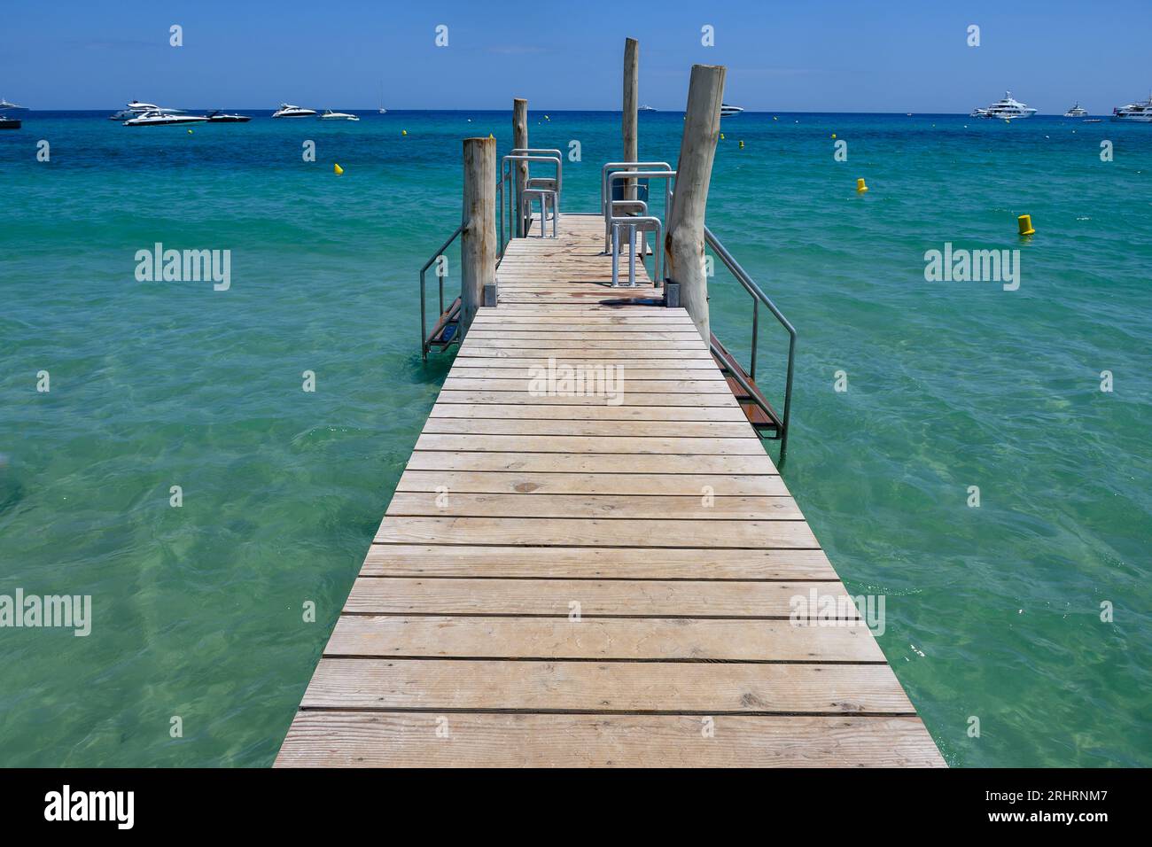 Wooden pier and crystal clear blue water of legendary Pampelonne beach ...