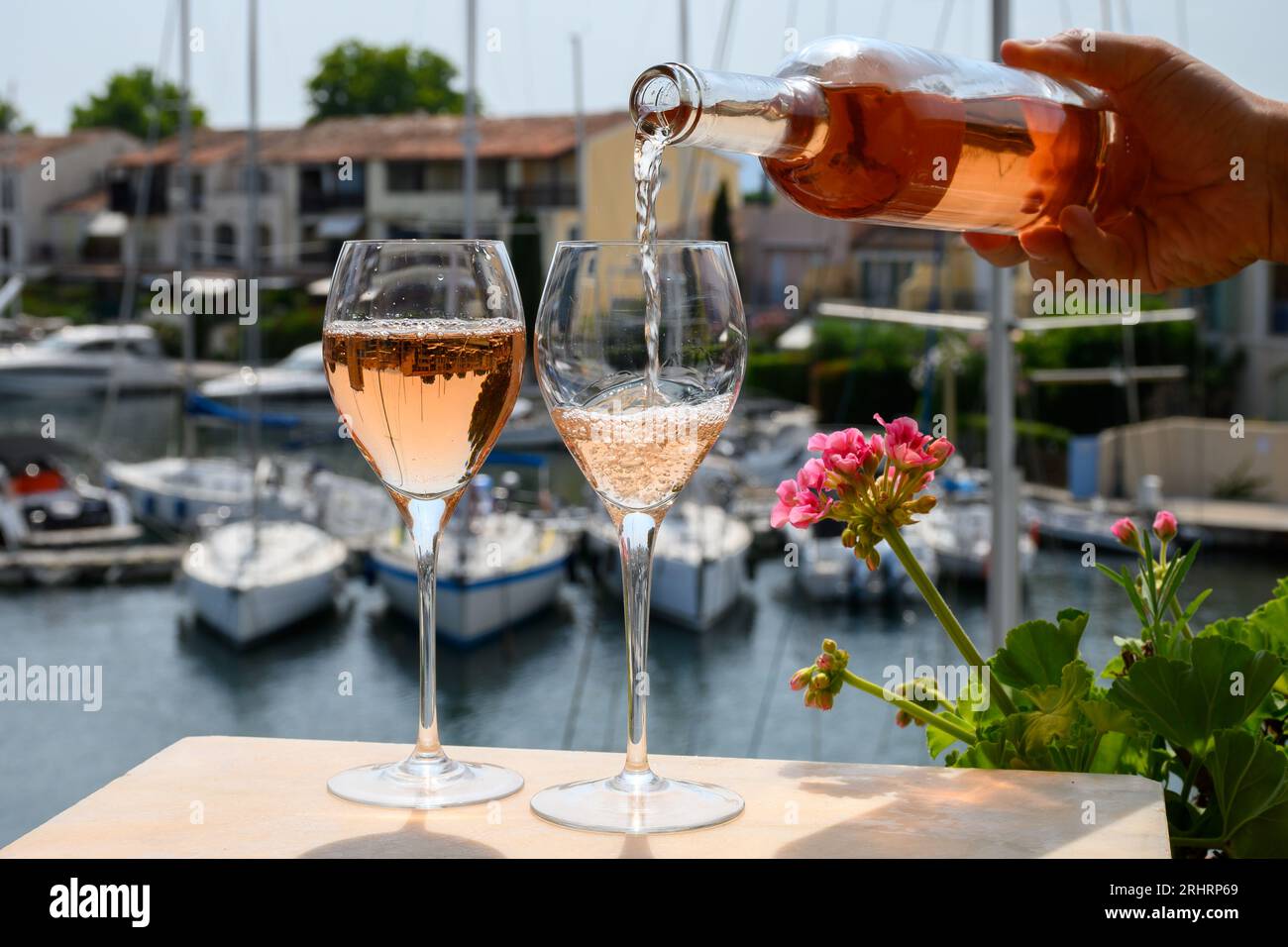 Pouring in glasses of cold rose Cote de Provence wine in yacht harbour ...