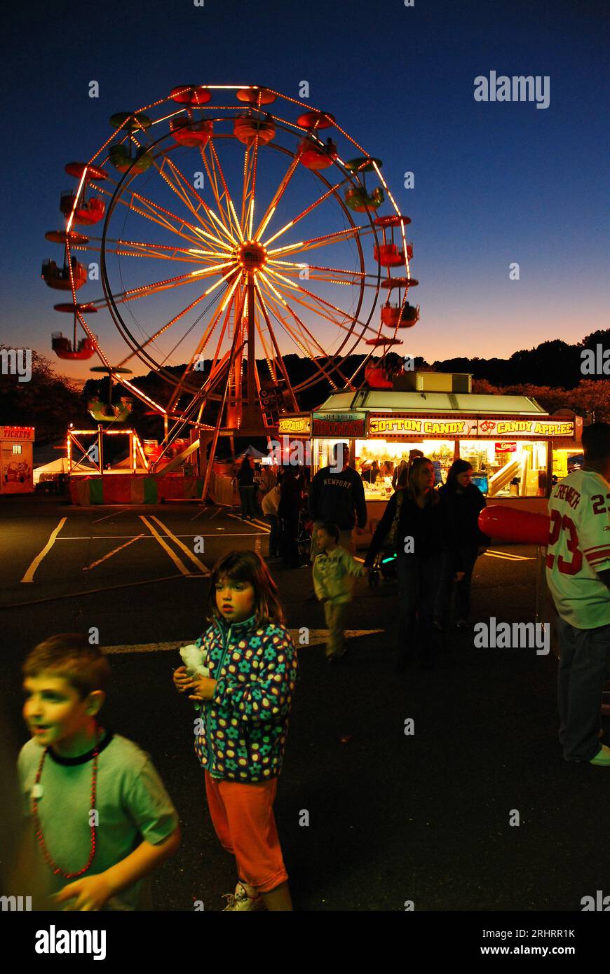 Two children enjoy a night at the state fair, watching the lights of ...