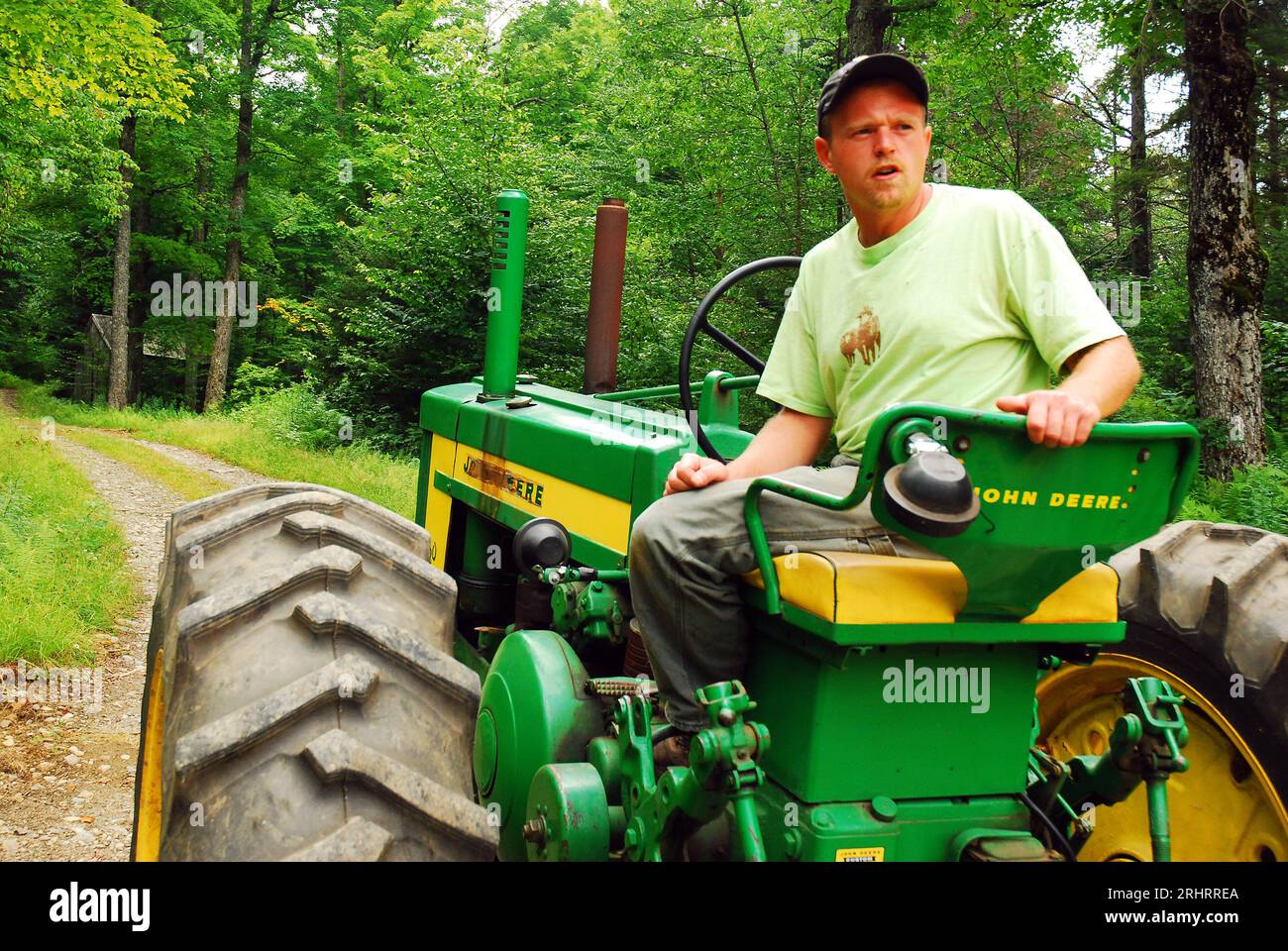 An adult man worker drives his tractor around the rural landscape of an ...