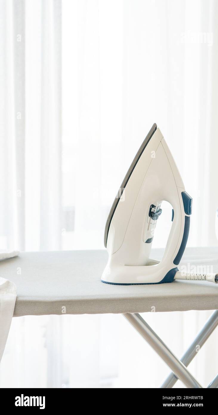 Steam iron standing on ironing board near window with copy space Stock ...