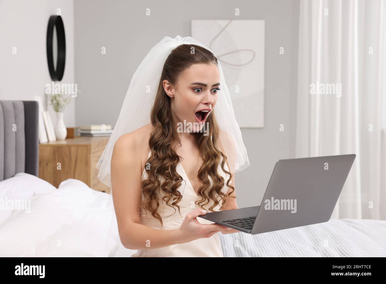 Shocked bride with laptop on bed in bedroom Stock Photo - Alamy
