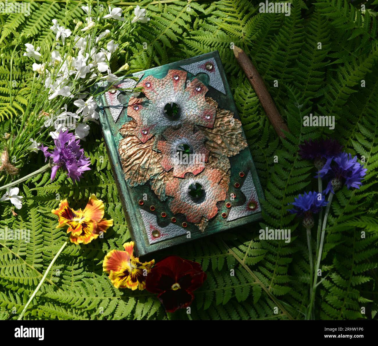 Still life with beautiful magic book of spells and flowers against ...