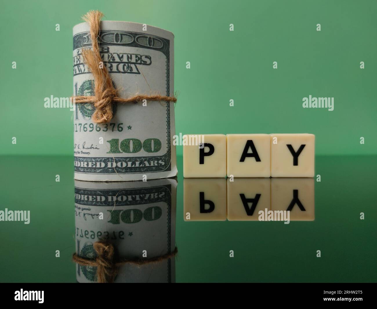 Toy word and banknote with text PAY on green background with reflection ...