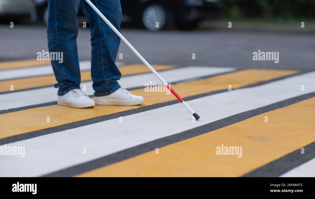 Close-up of the legs of a blind woman crossing the road at a crosswalk ...