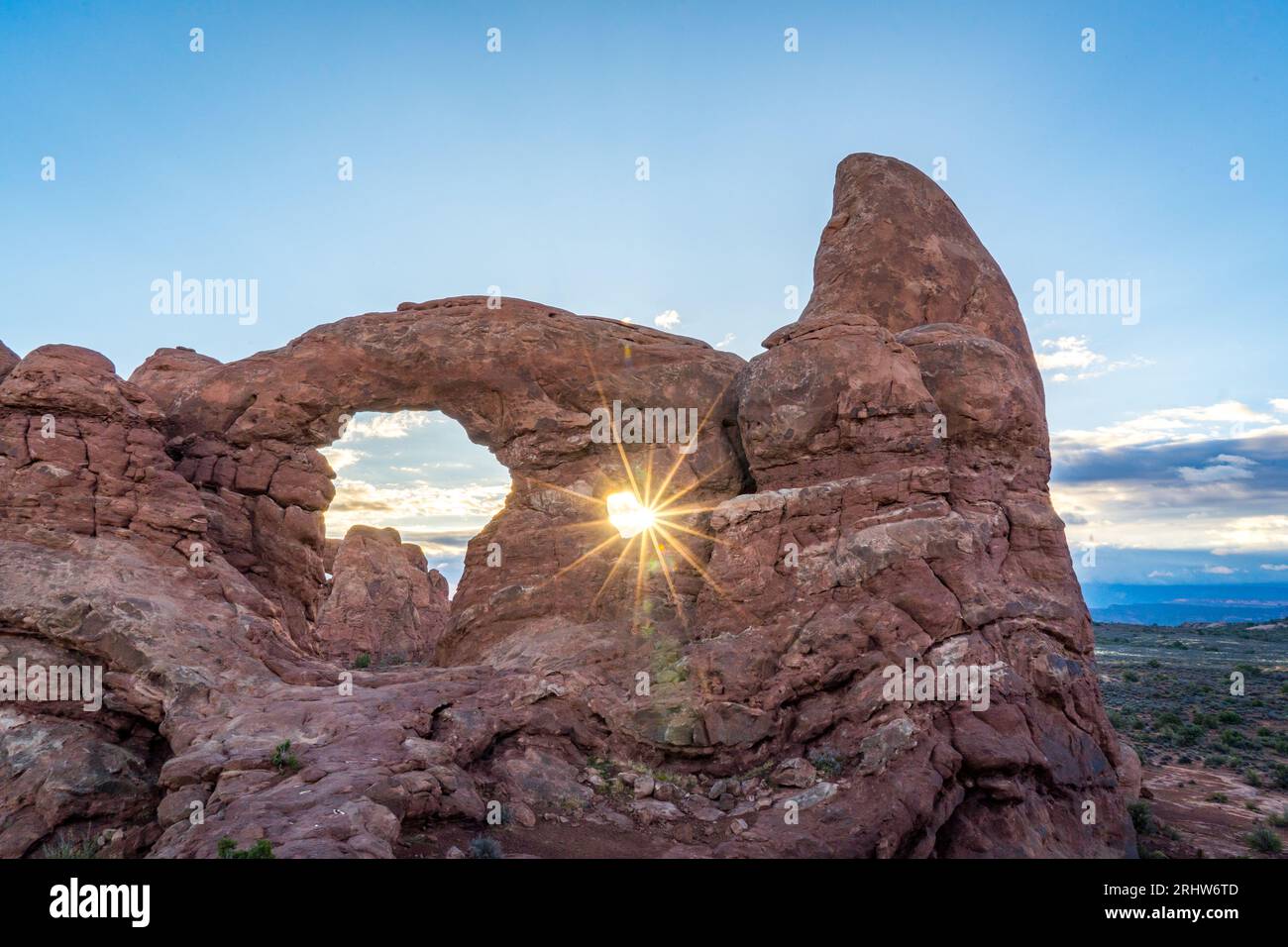 sun rising and shining through turret arch at arches national park in ...