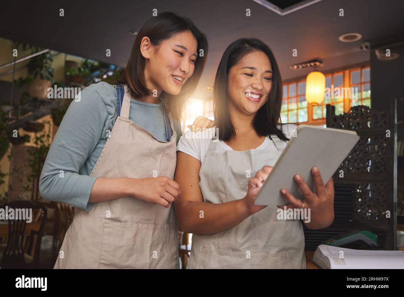 Restaurant, tablet and asian women checking sales, booking or menu promo for small business at ...