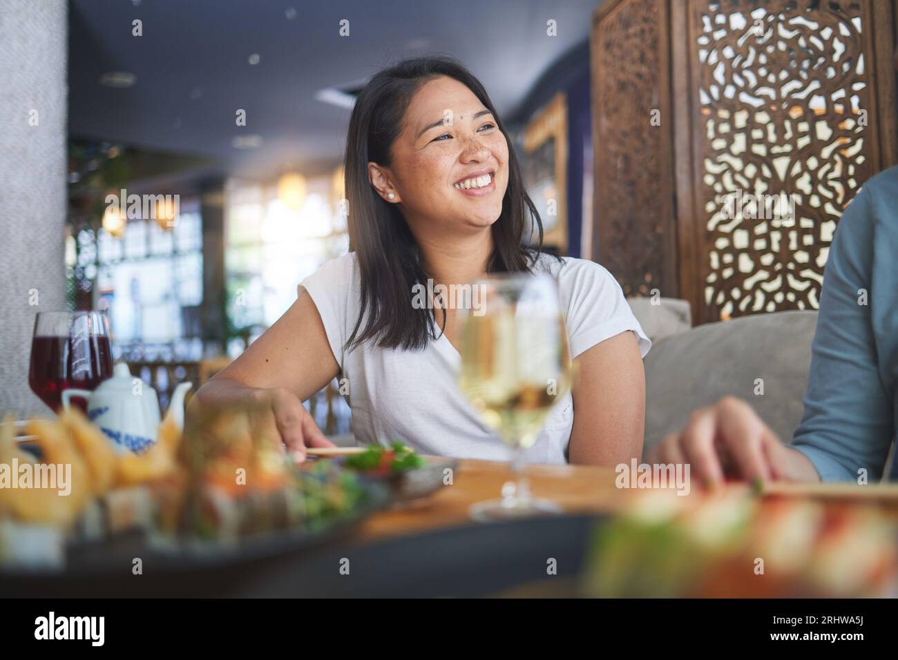 Japanese woman, sushi restaurant and smile for eating, thinking and conversation for fine dining ...