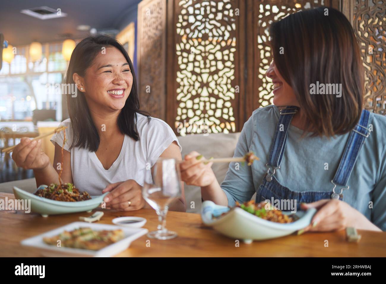 Chopsticks, girl friends and funny joke with restaurant food, noodles ...