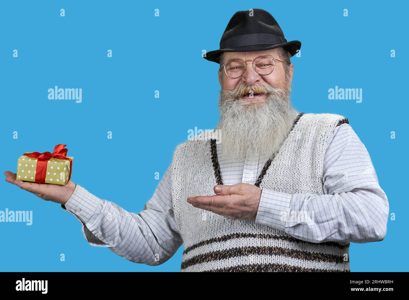 Old man urges to take a look at his gift box. Isolated on blue Stock ...