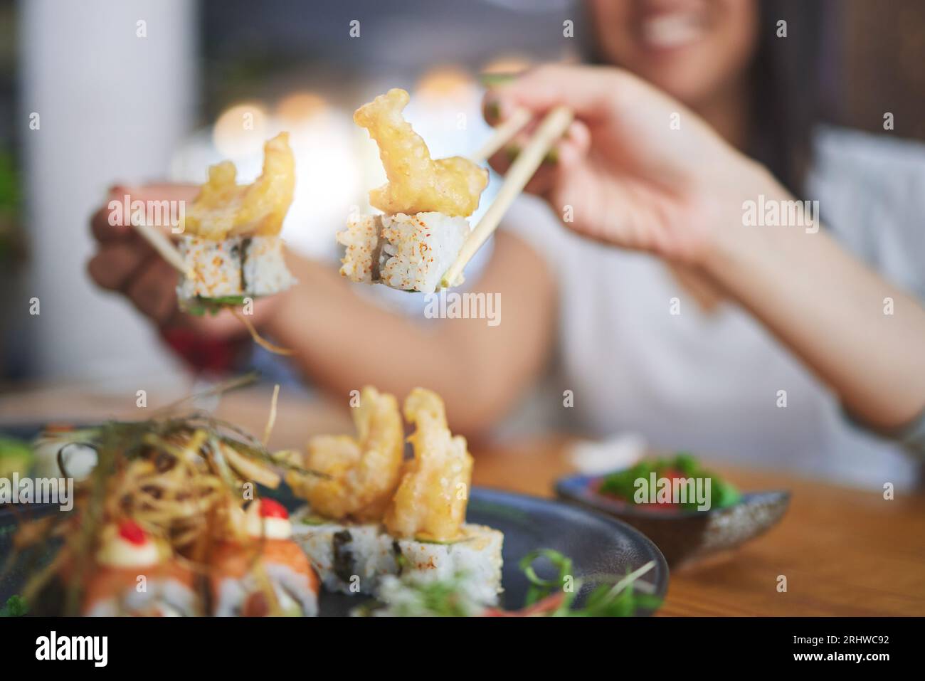 Chopsticks, girl friends hands and shrimp sushi at a table with ...