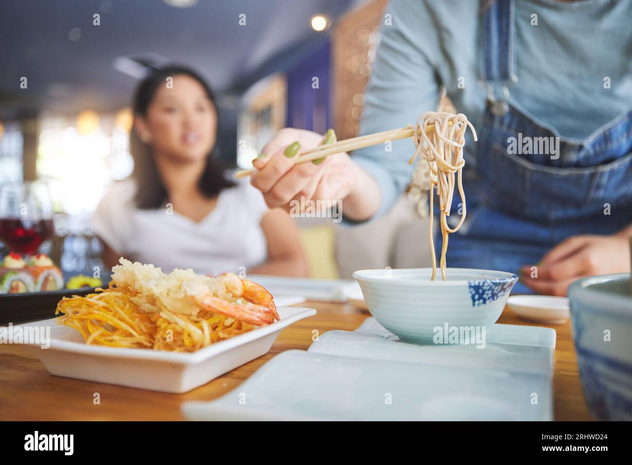Hand, ramen and chopsticks for Chinese food with a woman closeup in a ...