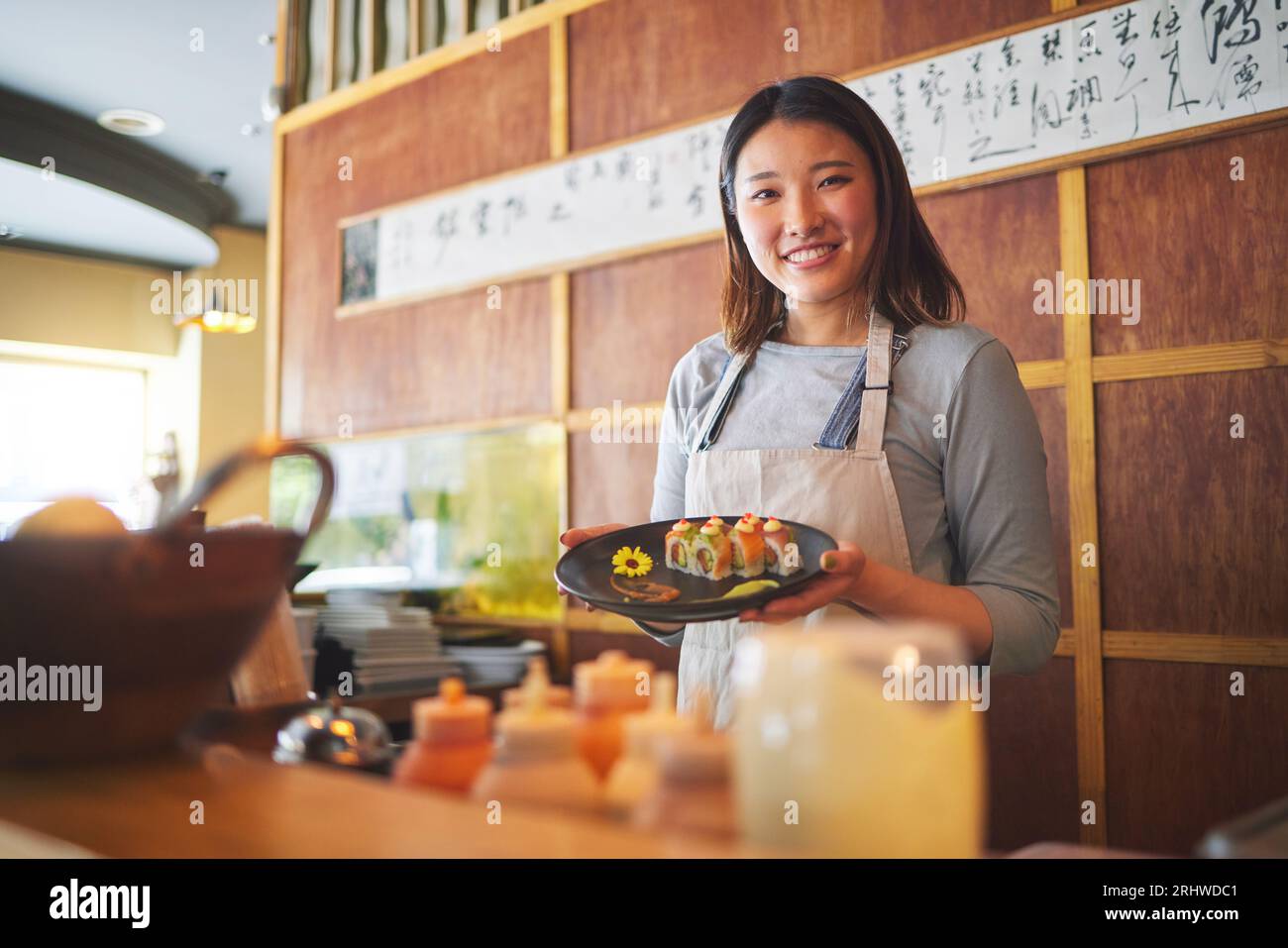 Sushi restaurant, portrait and female waitress with a plate for serving ...