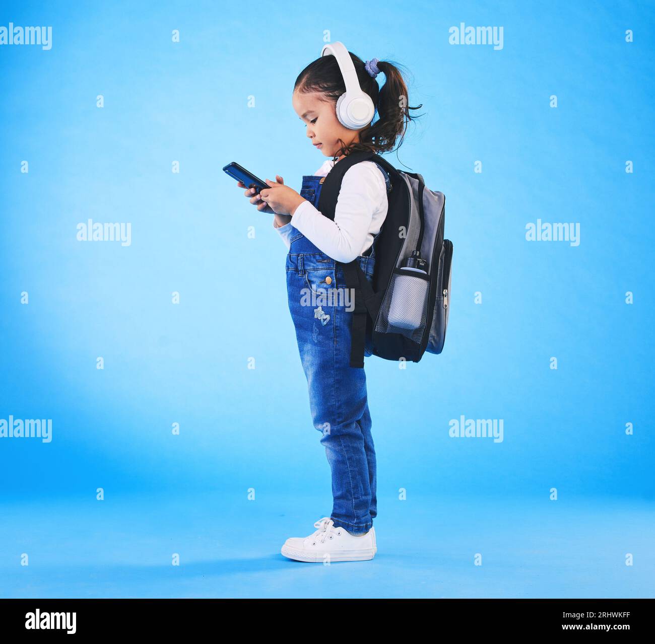 Headphones, backpack and child on blue background with phone ready for ...