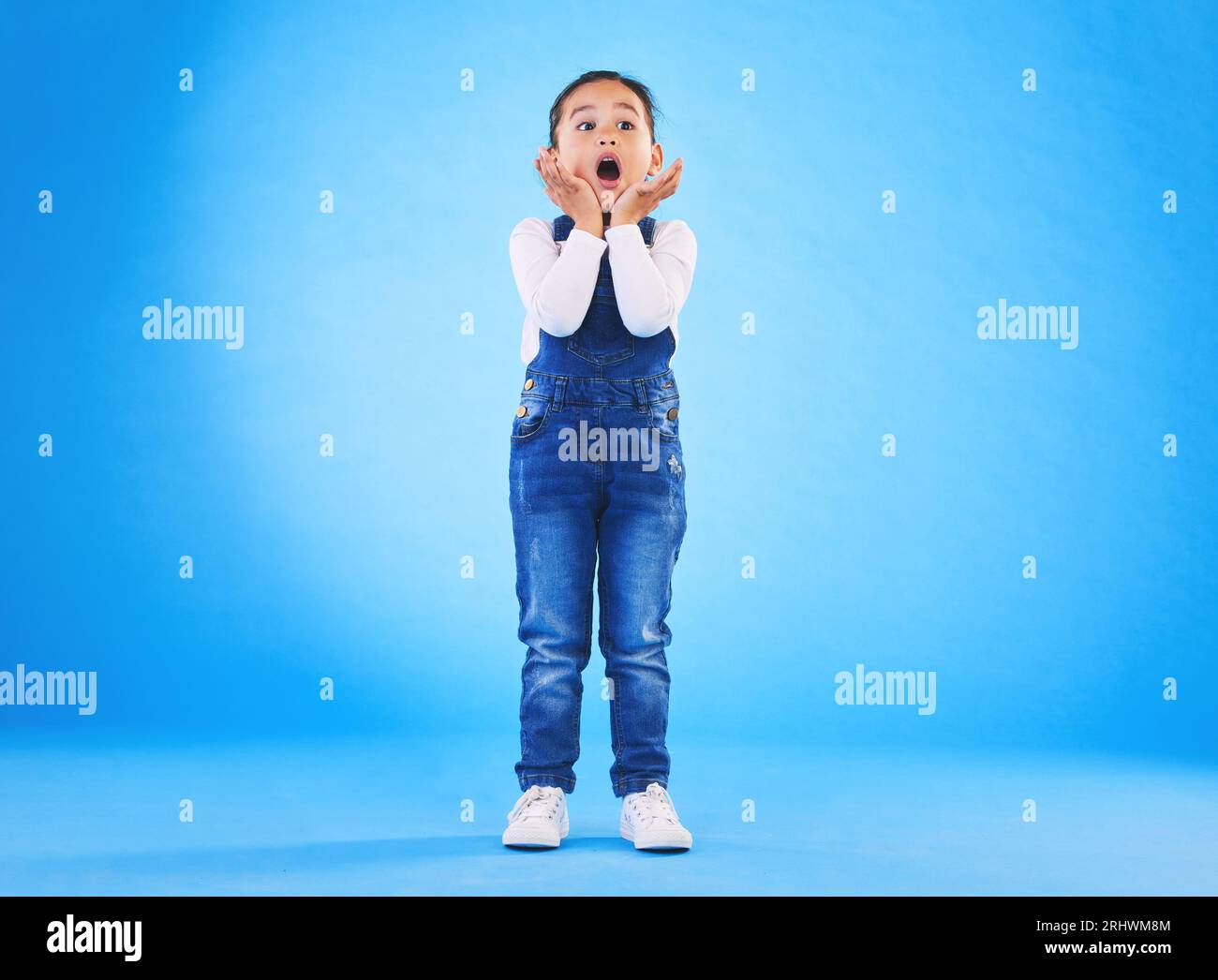 Shocked, wow and girl surprise with hands to face in studio with fear ...
