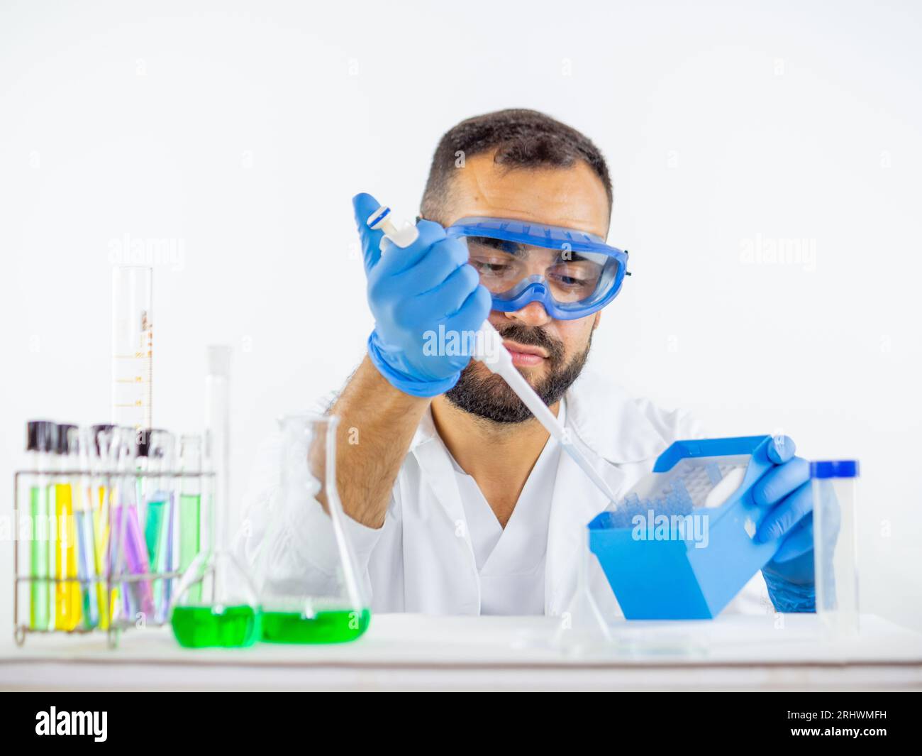 Young male doctor wearing protective glasses in a laboratory picking a ...
