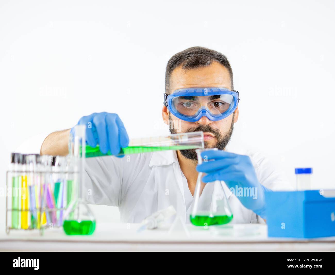 Young male scientist wearing protective glasses in a laboratory pouring ...