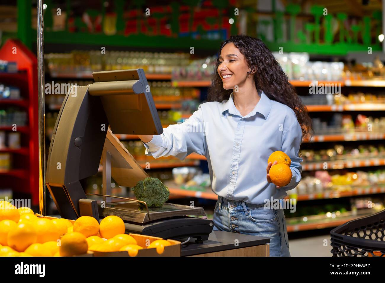 Young woman shopper in supermarket uses self-service scales, smiling ...