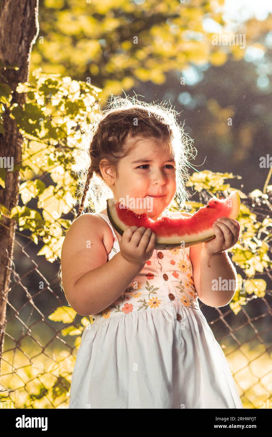 Cute little girl eating watermelon outdoors Stock Photo - Alamy