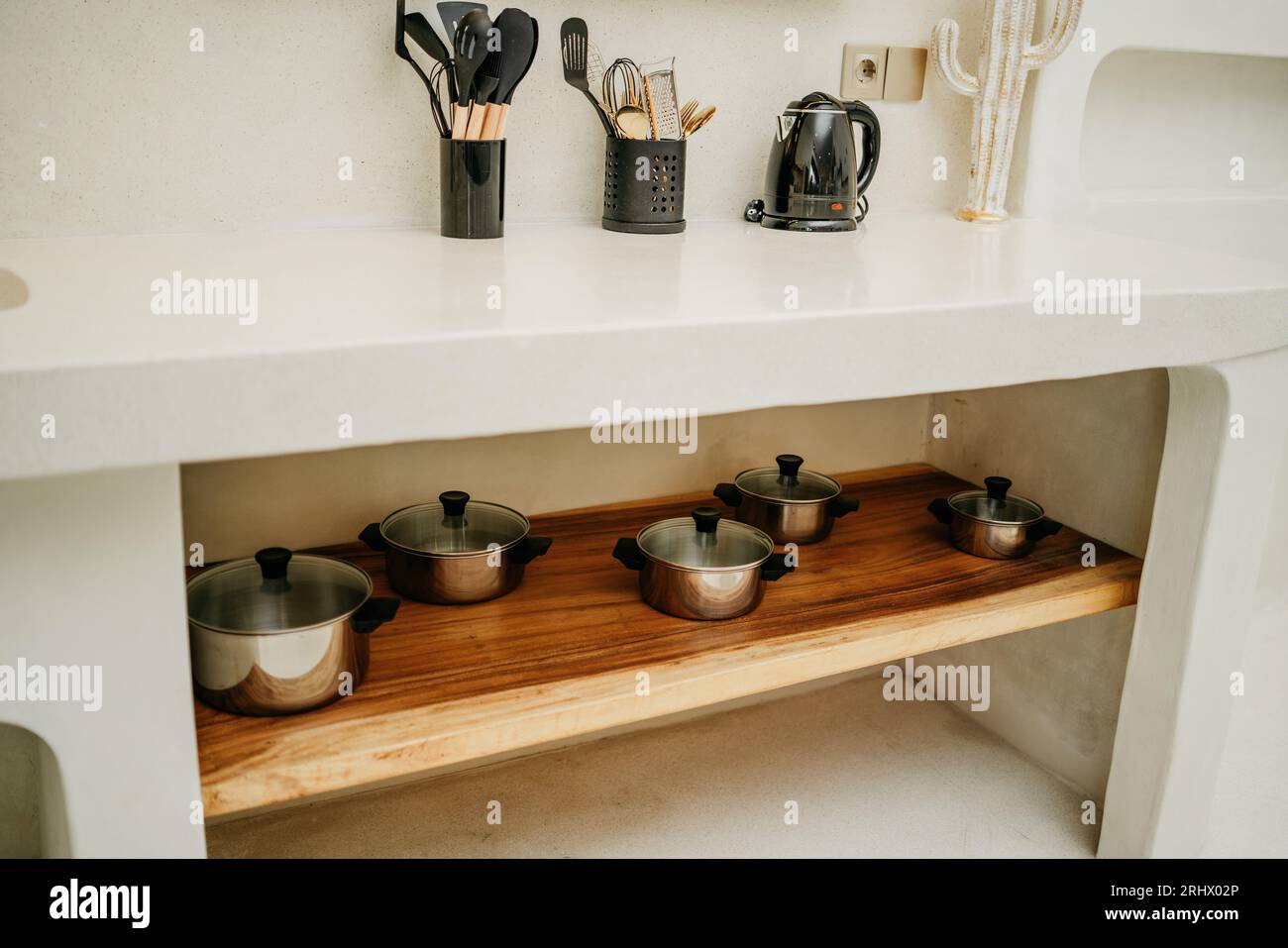 stainless steel pots with glass lids on wooden shelf. Kitchen stuff and ...