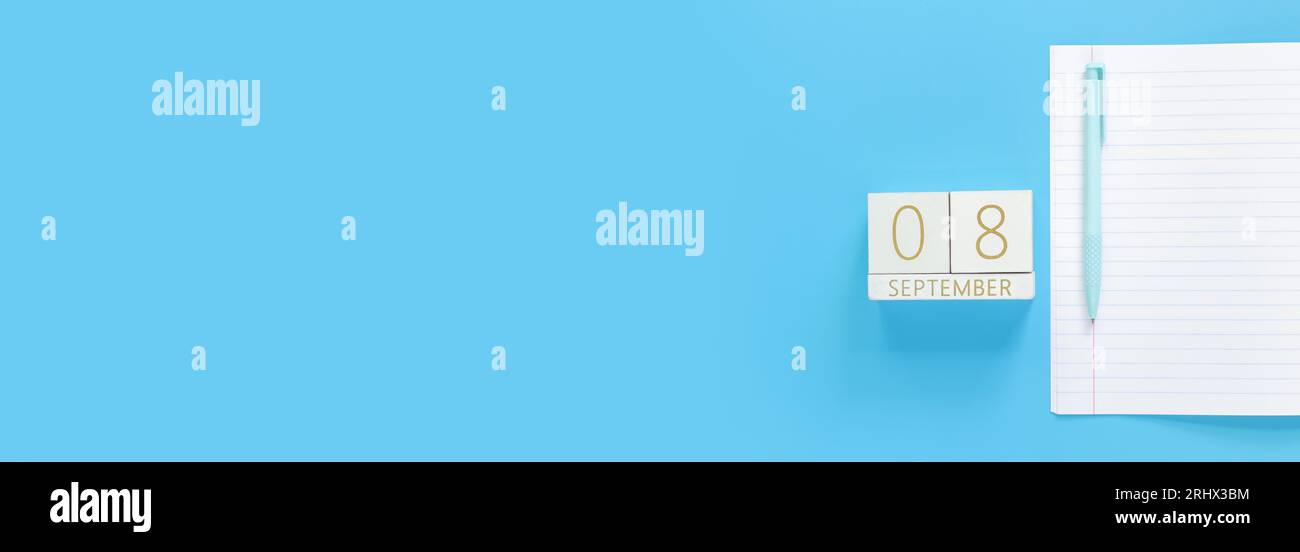 08 September. Wooden calendar on a blue background with an open notepad ...