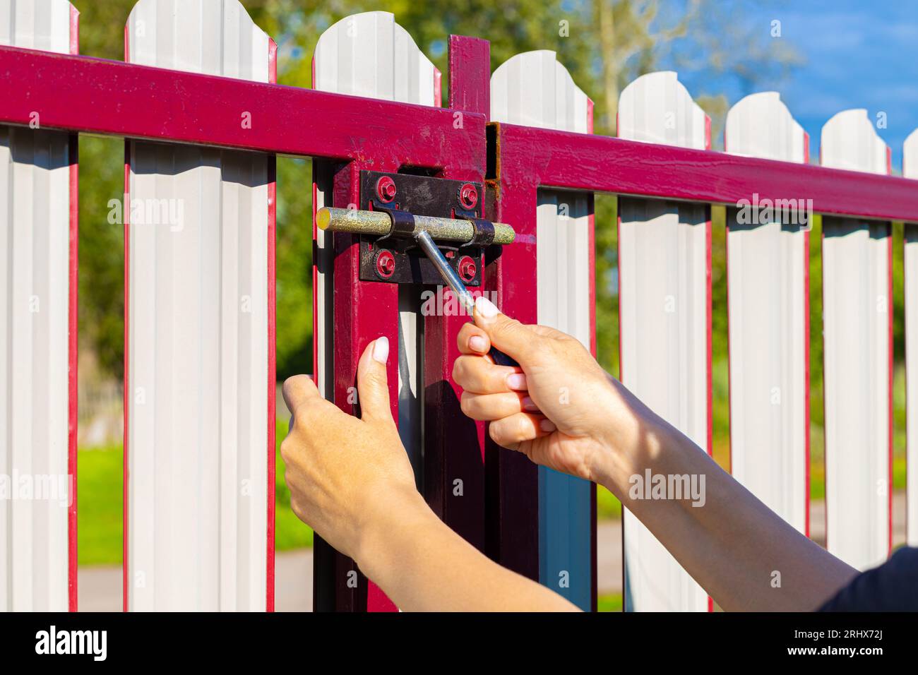 woman opens the bolt on the fence. hand opens the latch on the door ...