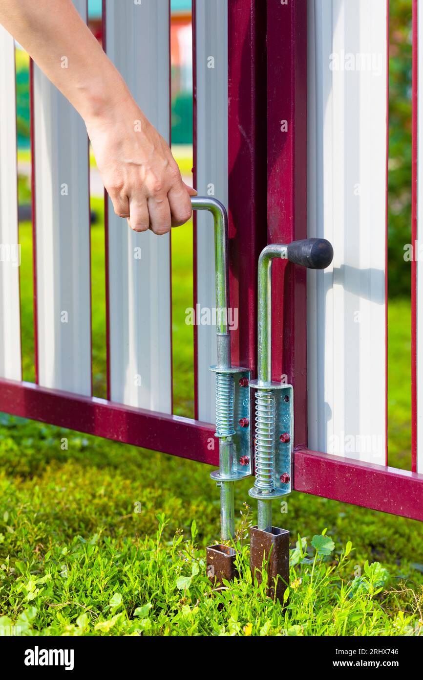 woman opens the bolt on the fence. hand opens the latch on the door ...