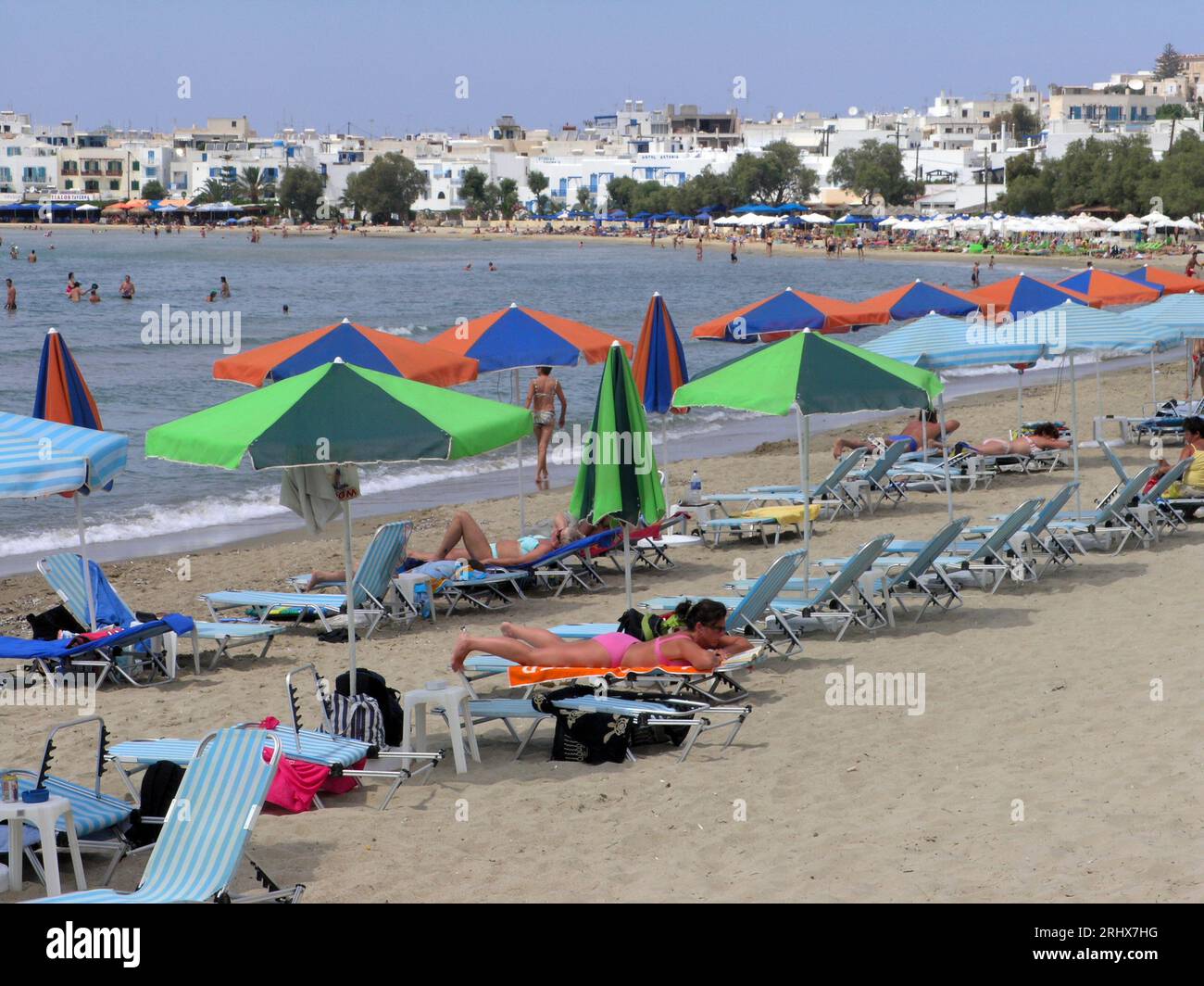 curved sandy beach along Aegean Sea, people, umbrellas, chaise lounges ...