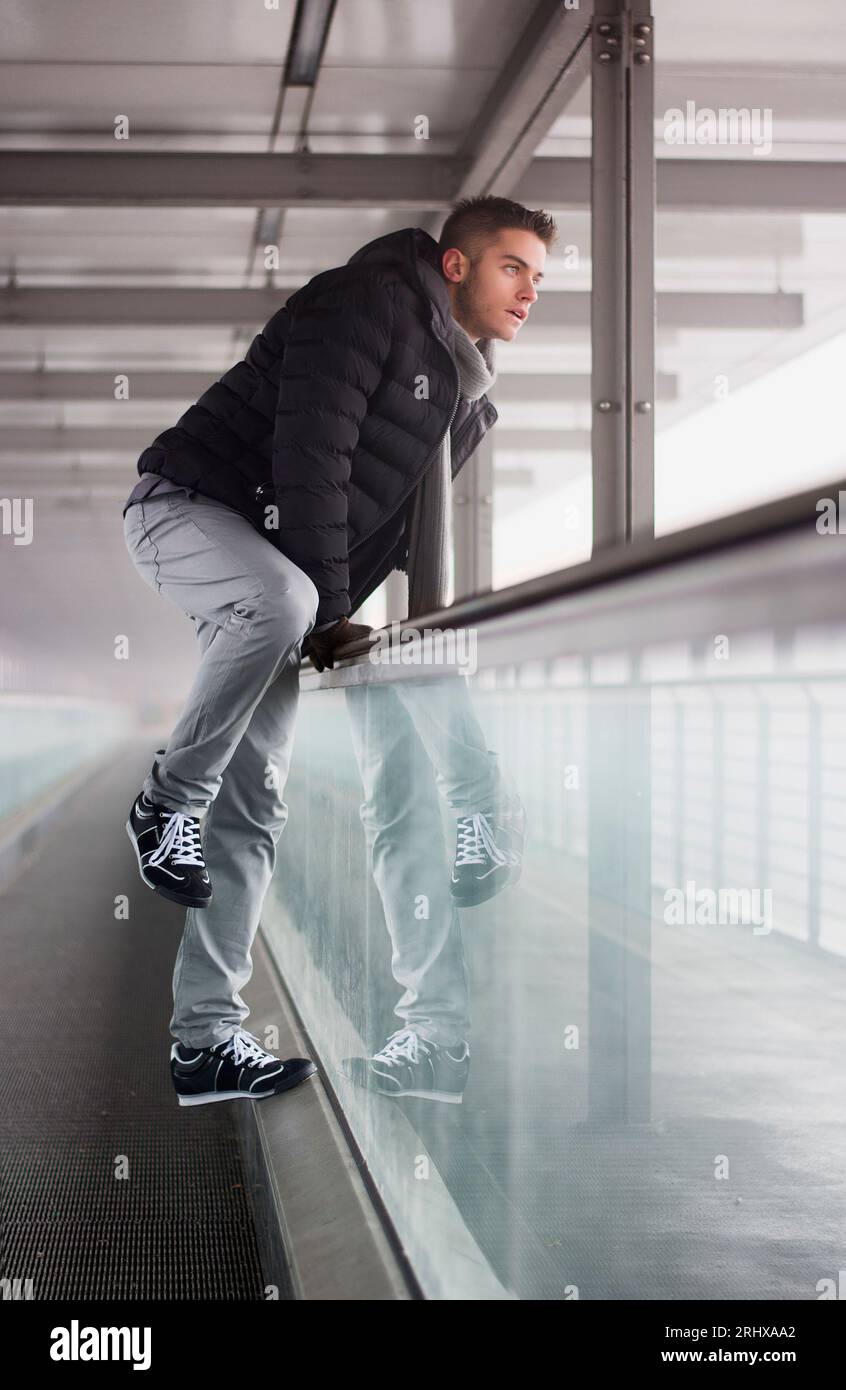 Photo of a man leaning against a glass wall in a modern building Stock ...