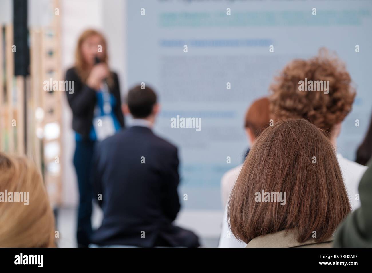 Back view of group of people gathering together in conference hall and ...