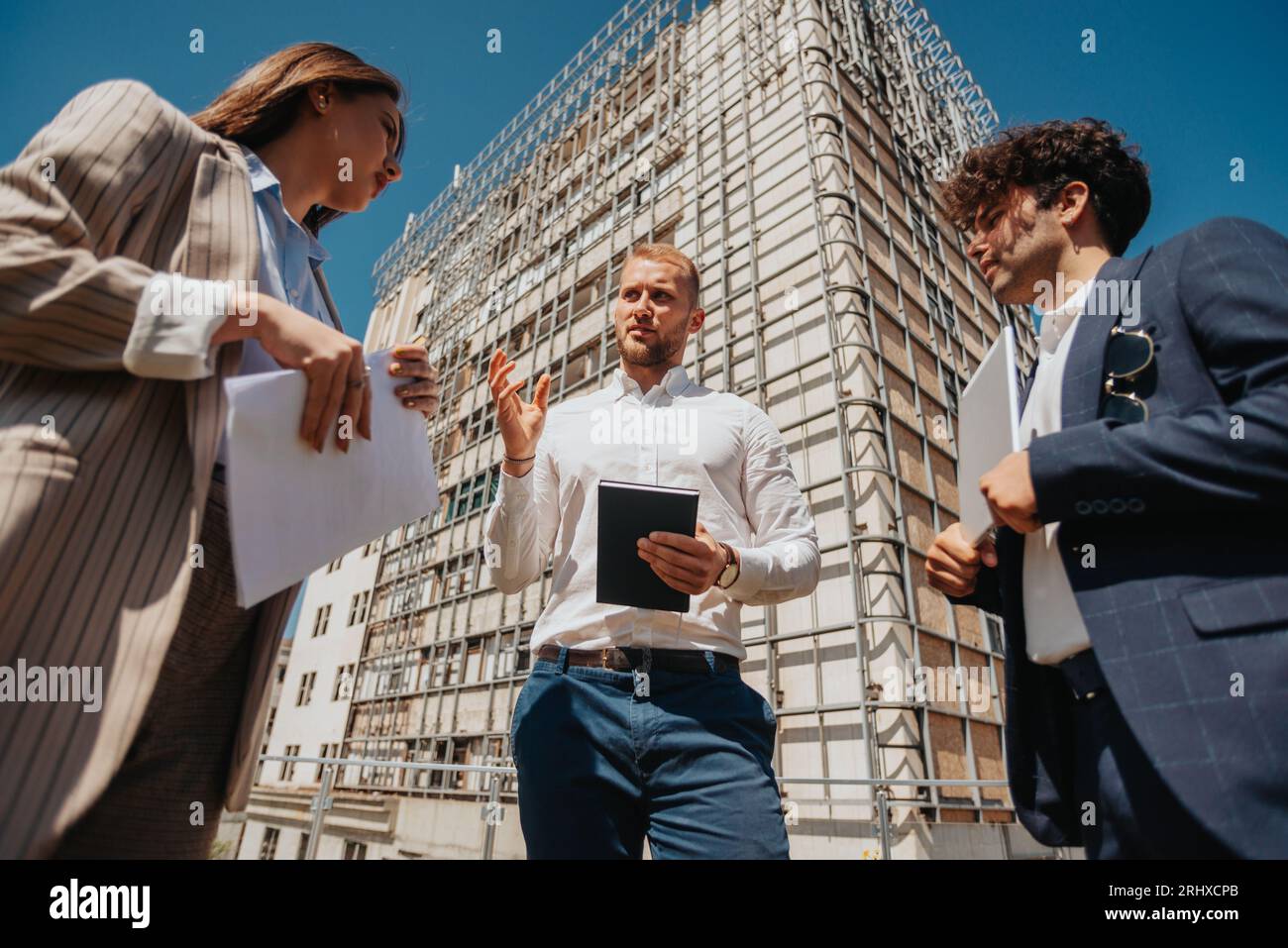Construction specialists walking through construction site. Discussing ...