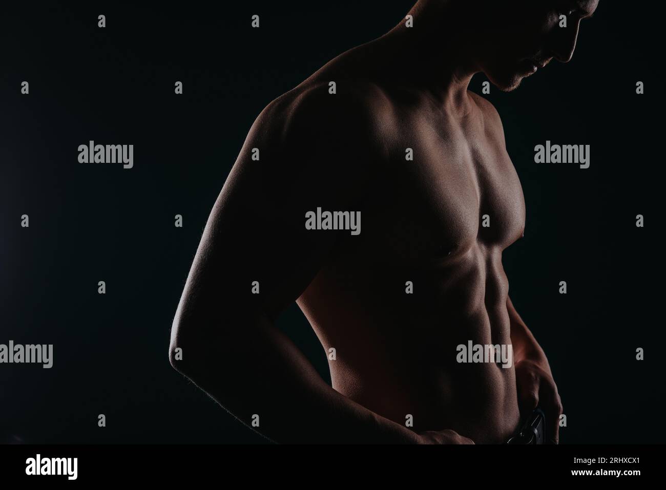 Stunning and well-built man standing in a dark room and posing Stock ...