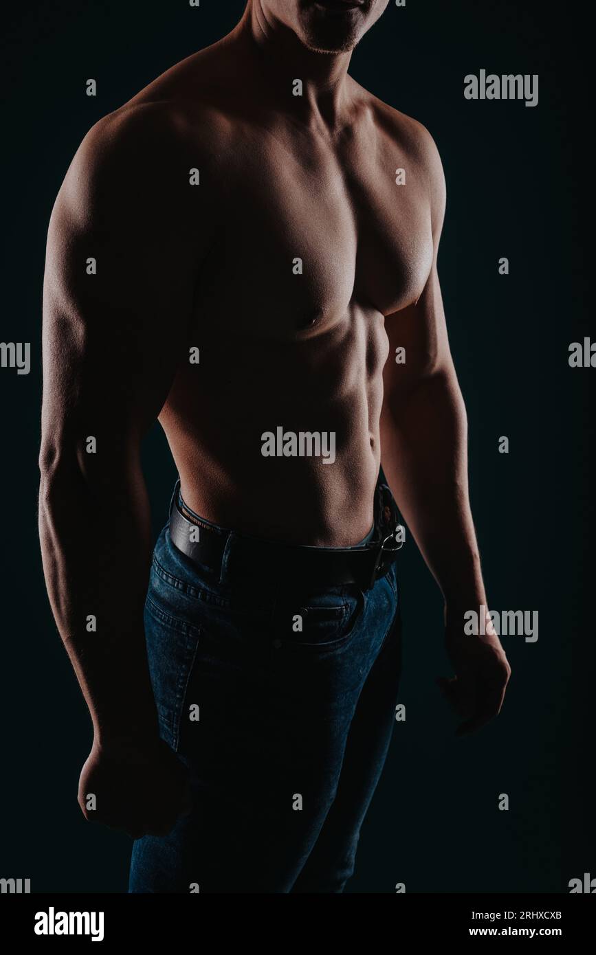 Good-looking and muscular man standing in a dark room and flexing his ...
