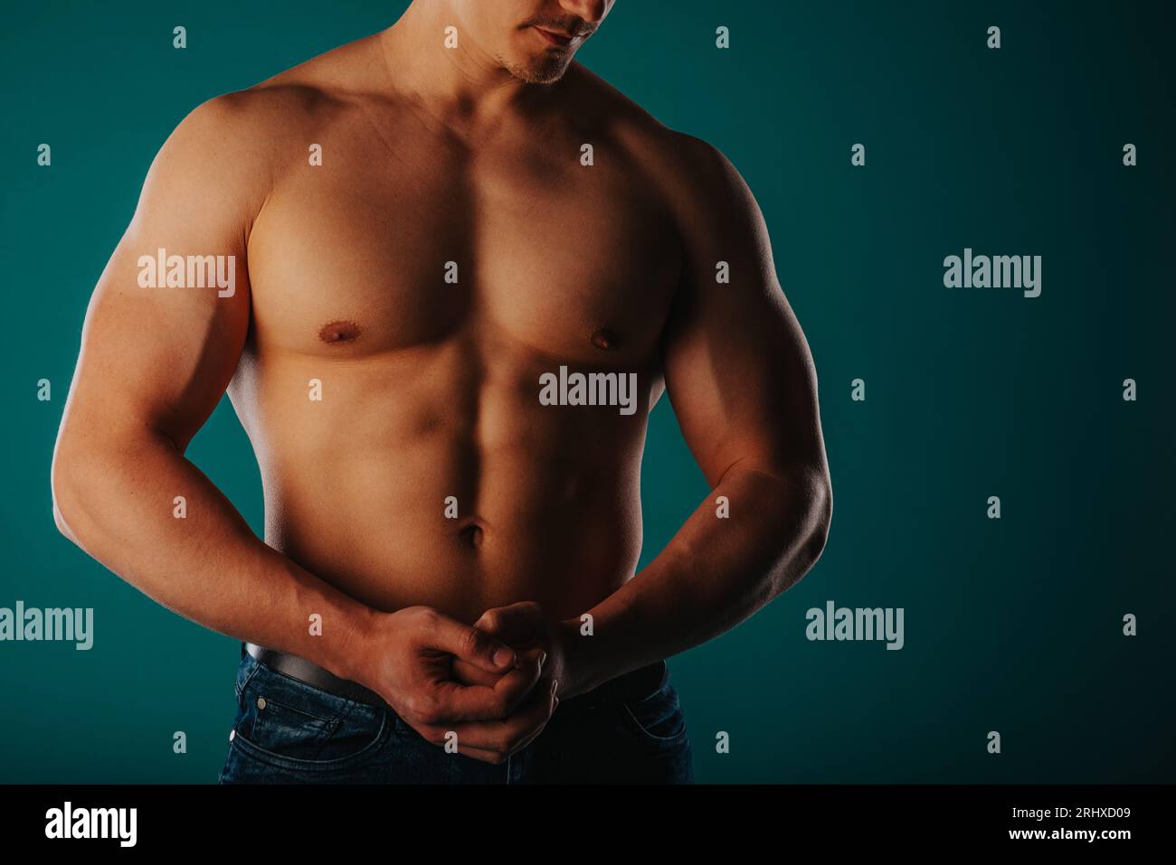 Fit male gym instructor posing in studio, showing his biceps, abs and ...