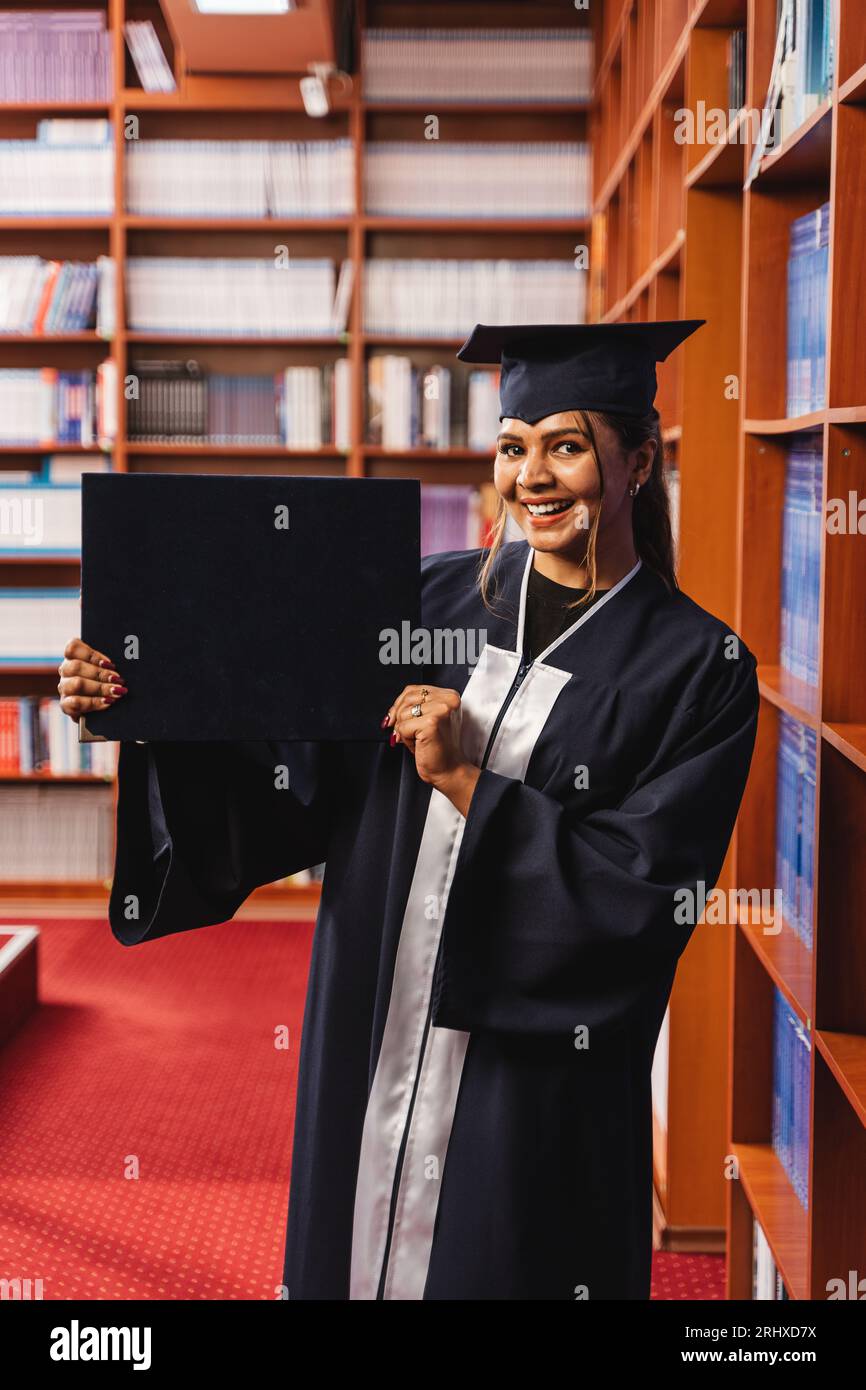 Young, happy and beautiful female graduate wearing her cap and gown ...