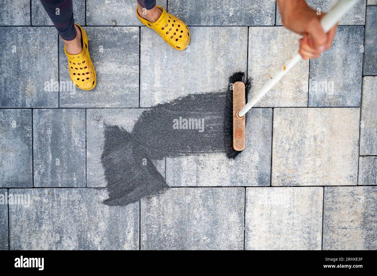 Overhead view of a woman dusting special sand for tile gap into the ...
