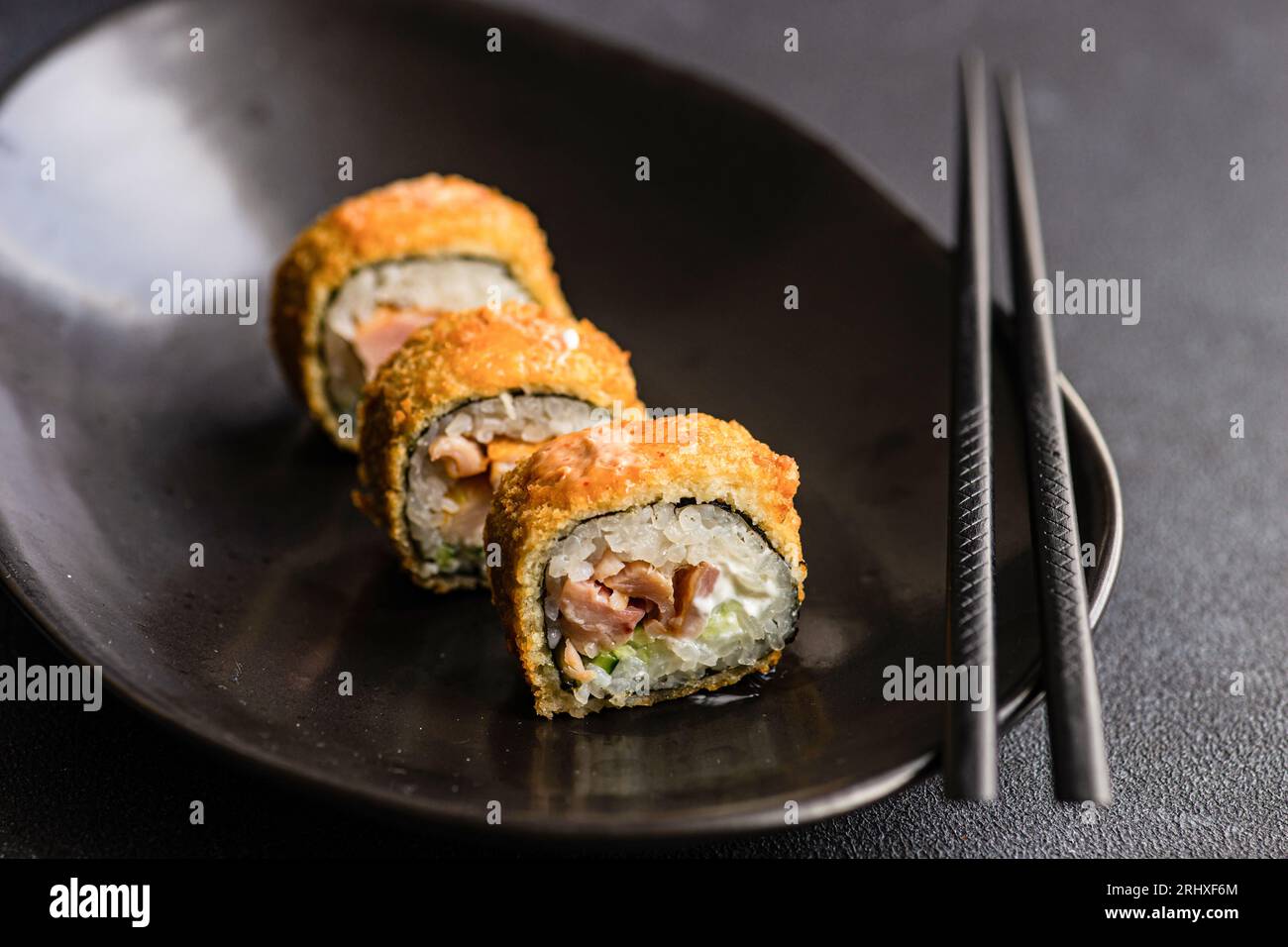 Focused row of tasty fried sushi rolls with cooked rice and salmon with ...