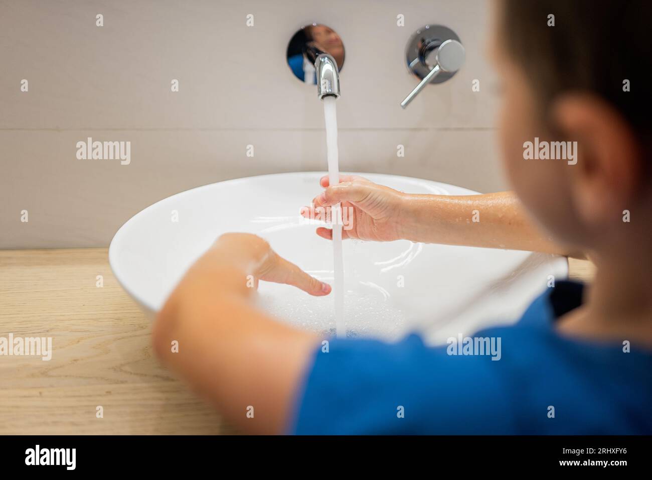 Anonymous kid washing hands at sink with pouring water from tap during ...